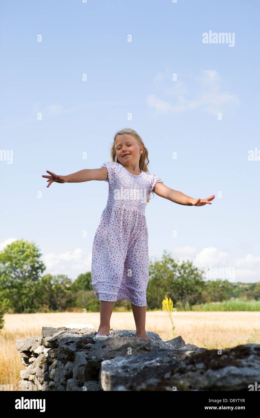 A girl balancing on a stone wall Stock Photo - Alamy