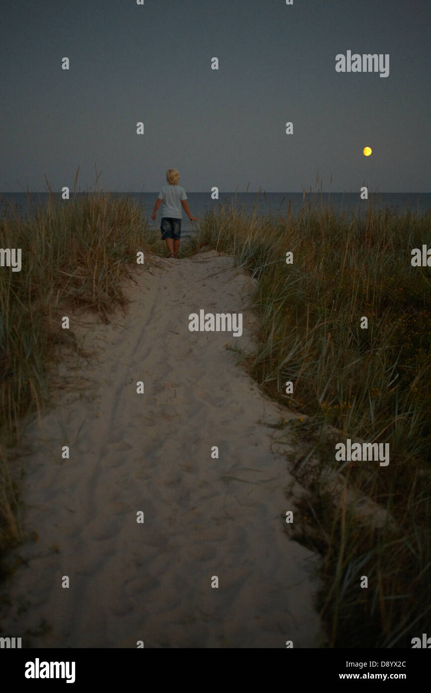 A boy on the beach under the moon Stock Photo - Alamy