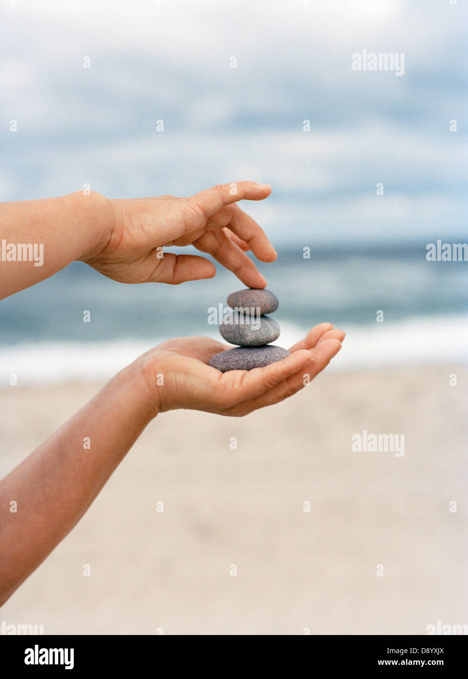 Hands holding stones with the ocean in the background Stock Photo - Alamy