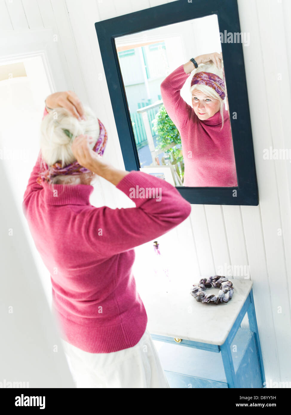 A woman fixing her hair in front of a mirror Stock Photo - Alamy