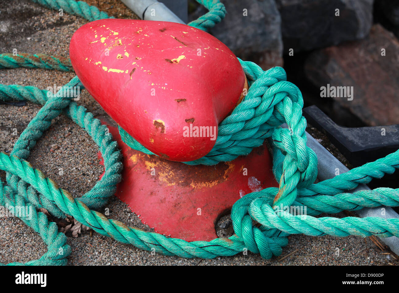 Red mooring bollard with green naval rope Stock Photo - Alamy