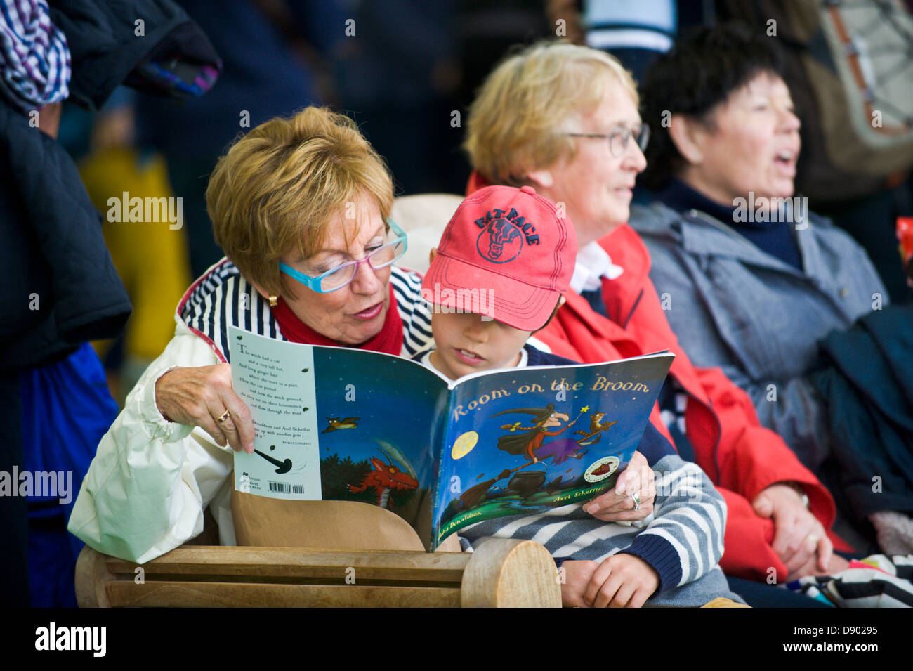 Woman reading book with young boy sat on bench at Hay Festival 2013 Hay ...