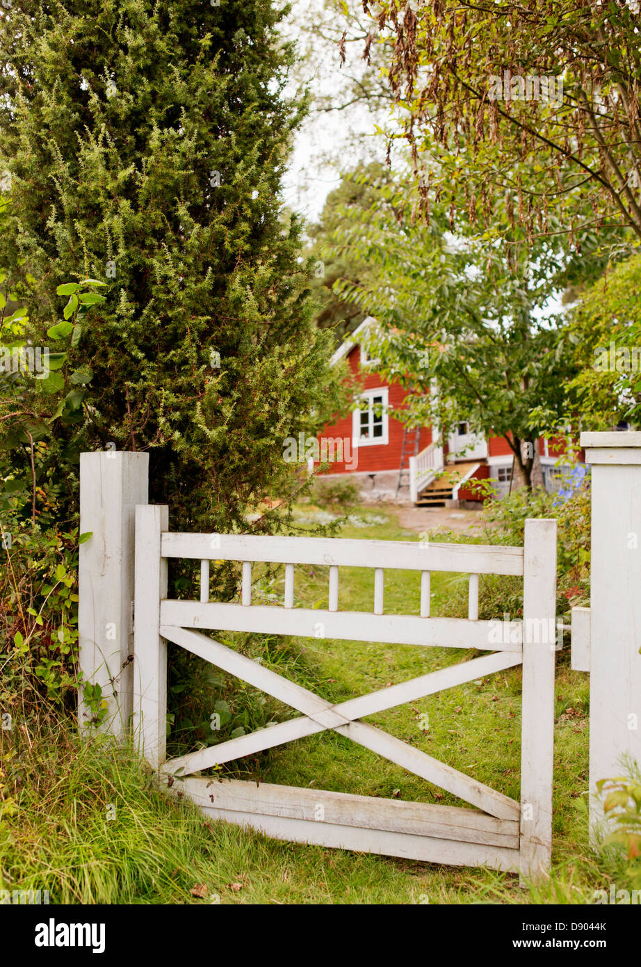 Wooden gate with red cottage in background Stock Photo - Alamy
