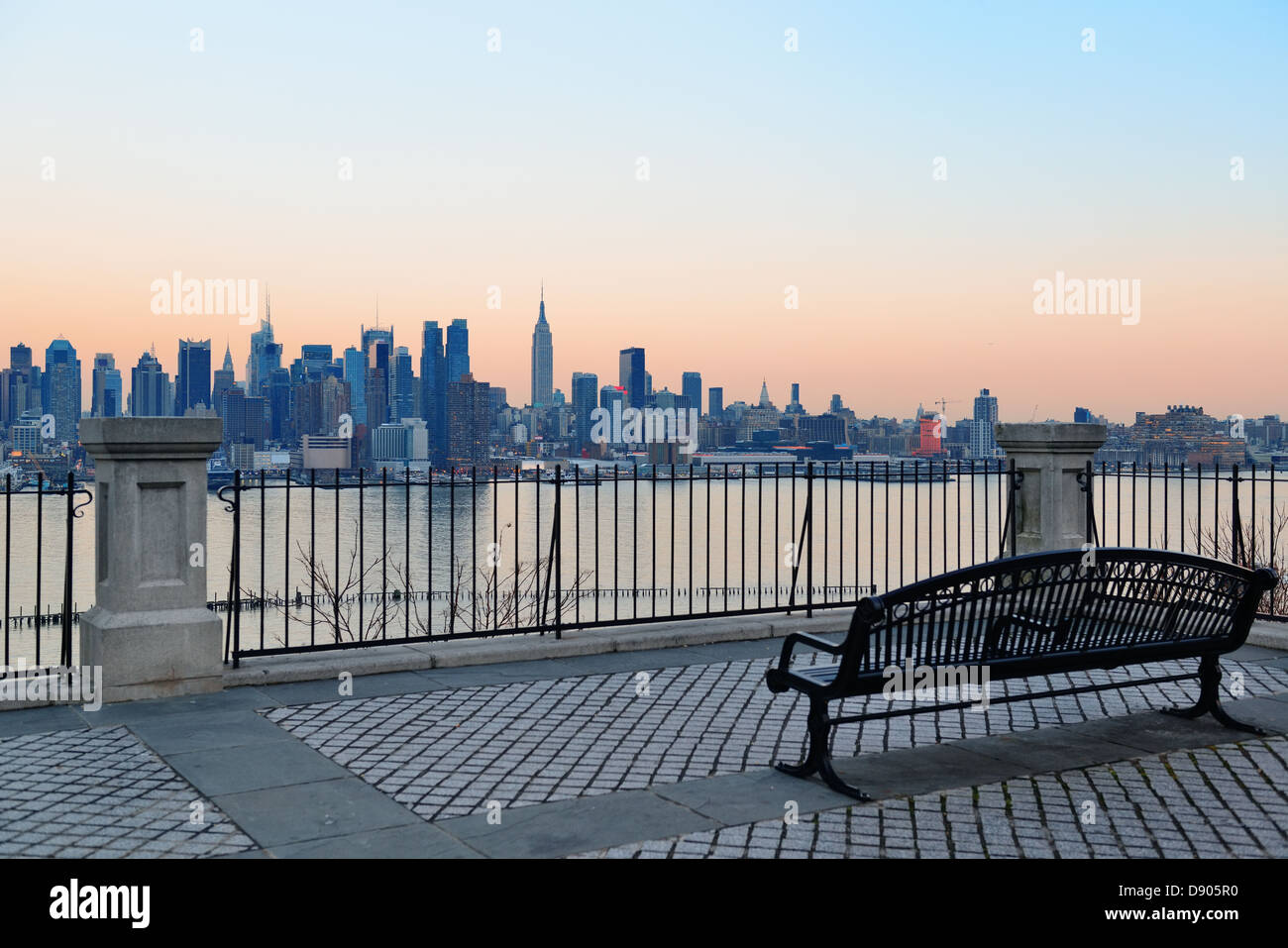 Bench in park and New York City midtown Manhattan at sunset with ...