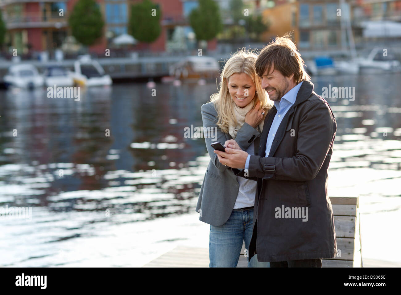 Couple standing on promenade using cell phone together Stock Photo - Alamy