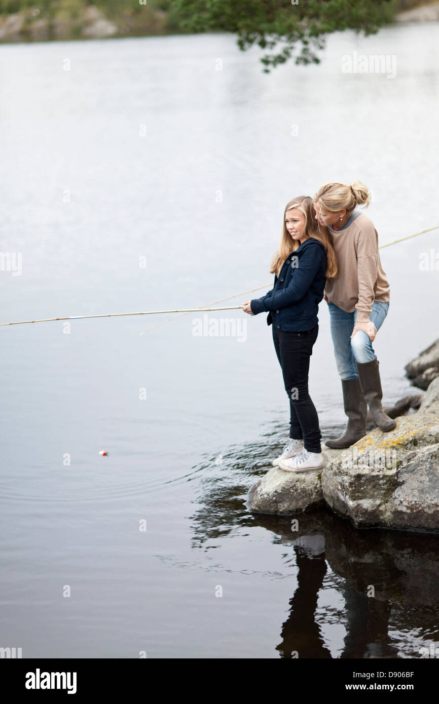 Daughter and mother fishing at lake Stock Photo - Alamy