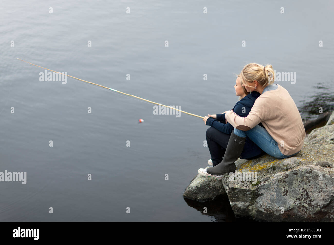 Daughter and mother fishing at lake Stock Photo - Alamy