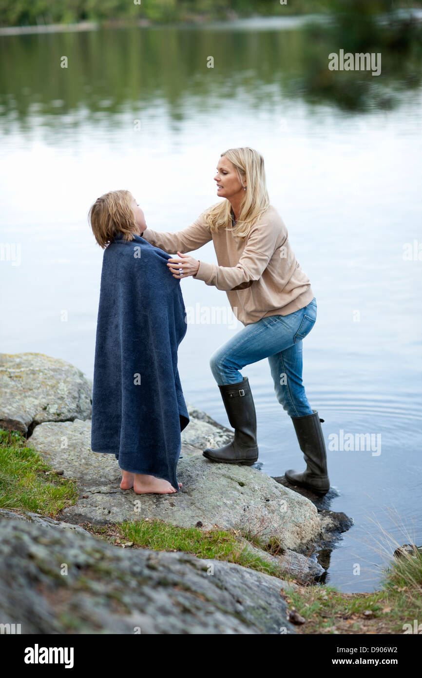 Mother drying son with towel at lake Stock Photo - Alamy