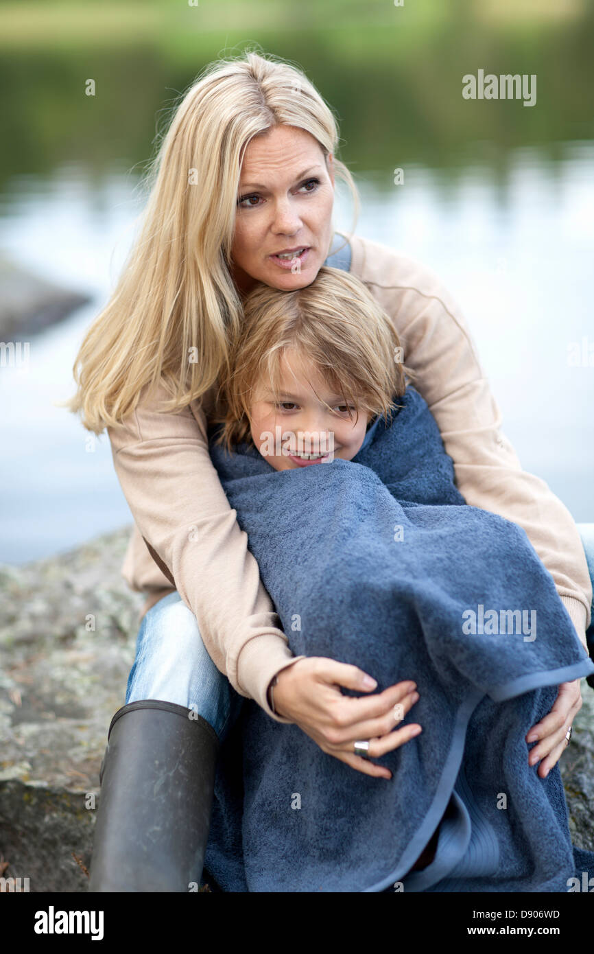 Mother drying son with towel at lake Stock Photo - Alamy