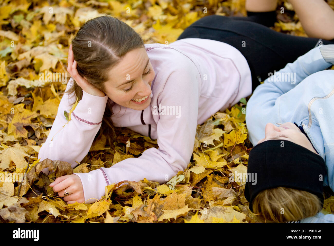 Two women laying down in the autumn leaves Stock Photo - Alamy