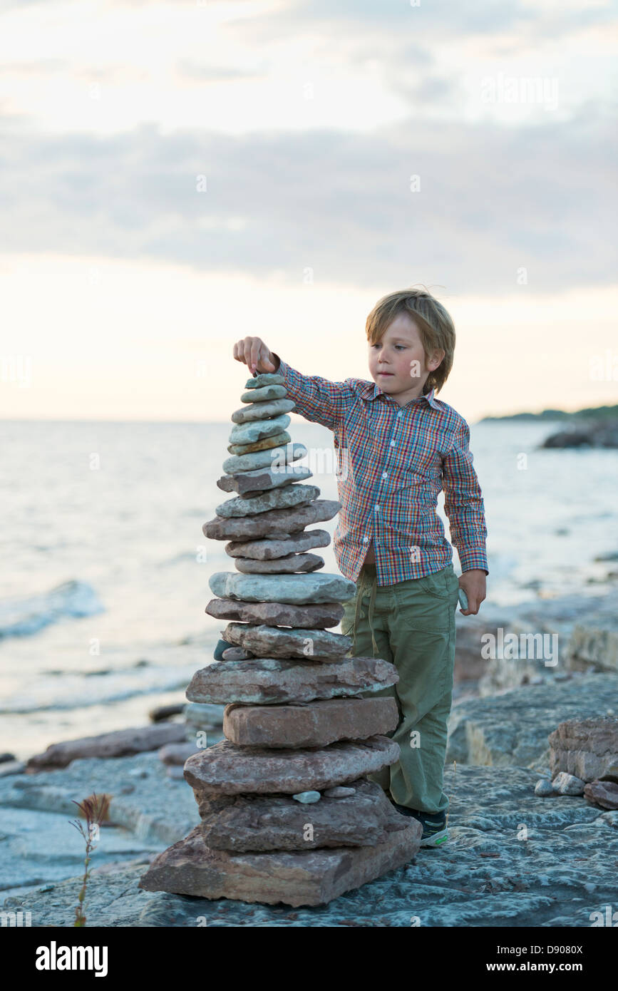 Boy on beach stacking rocks Stock Photo - Alamy