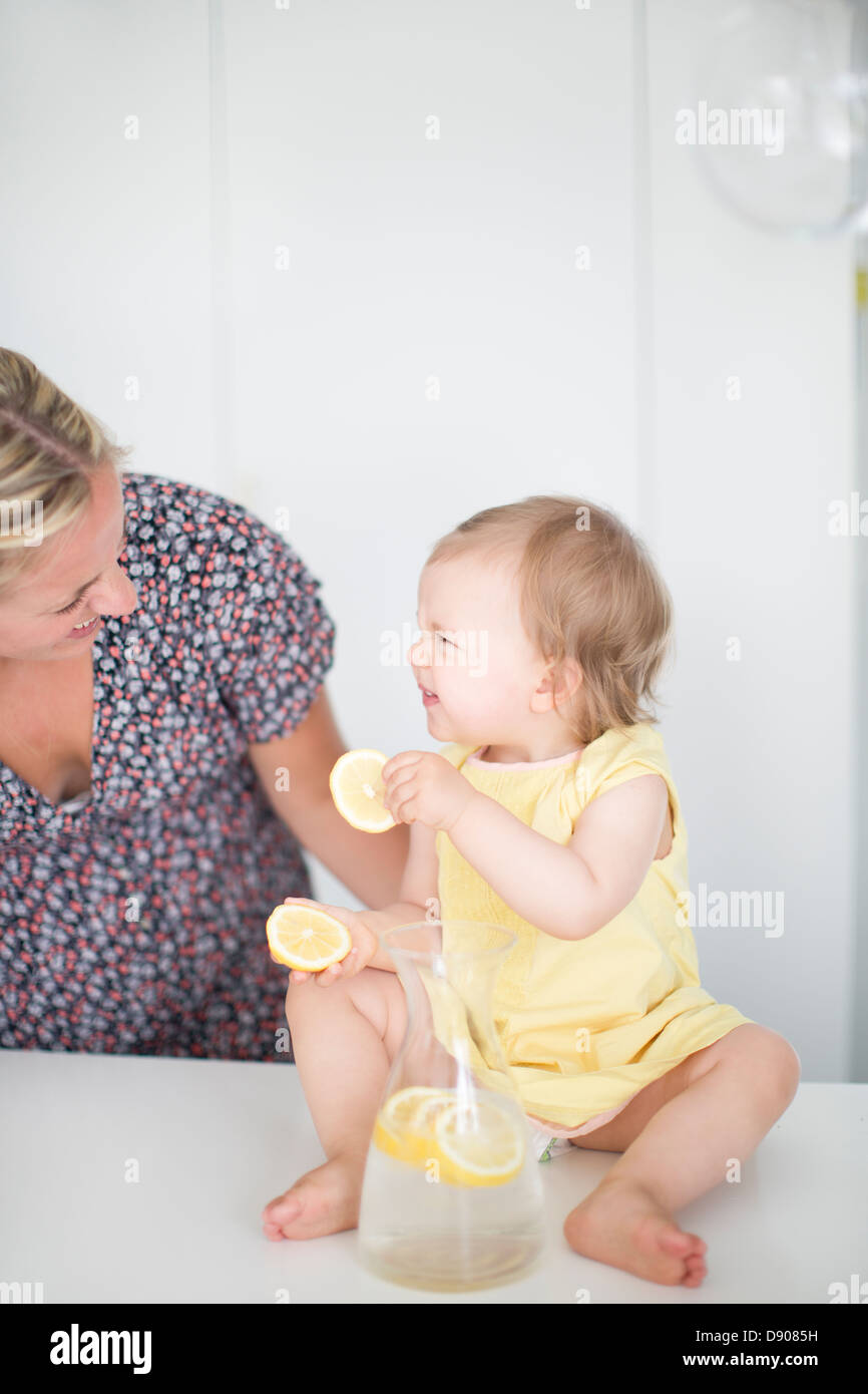Little girl holding slices of lemon and smiling to mother Stock Photo ...