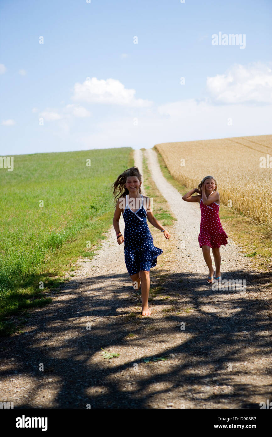 Two girls running on a country road Stock Photo - Alamy