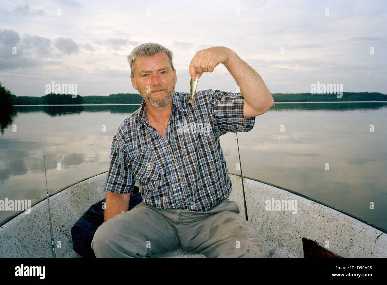 Man showing his take, a small fish Stock Photo - Alamy