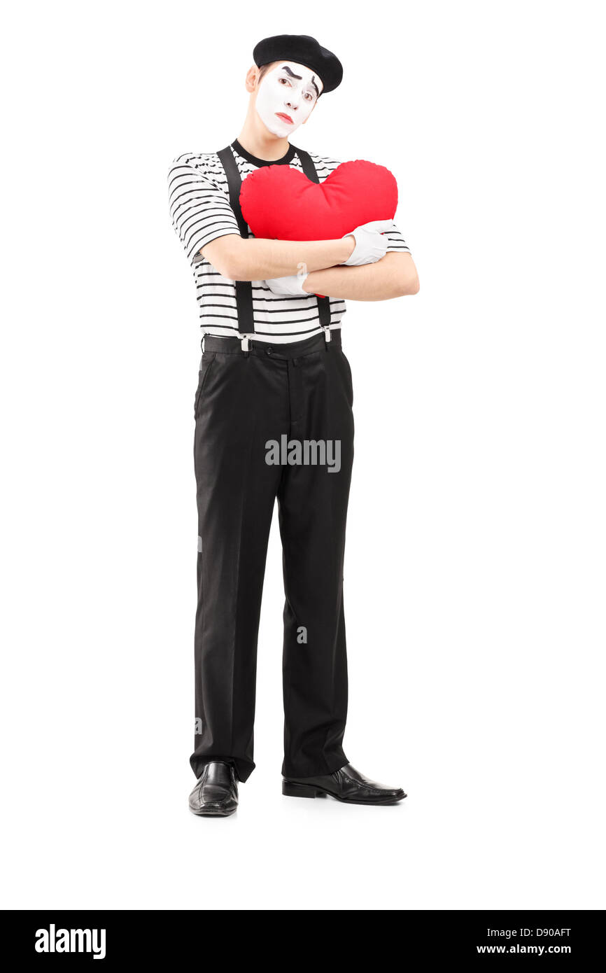 Full length portrait of a sad mime artist holding a red heart isolated ...