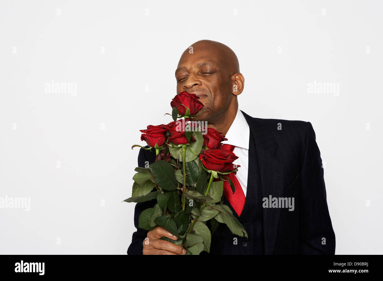 A man in a suit holding a bunch of red roses Stock Photo - Alamy