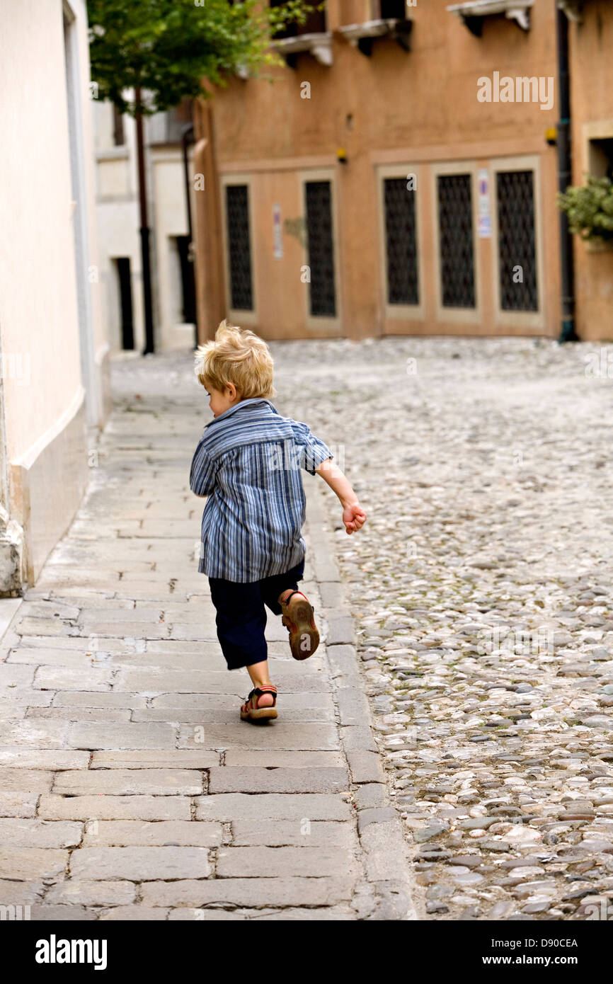 A very young boy running away from the photographer Stock Photo - Alamy