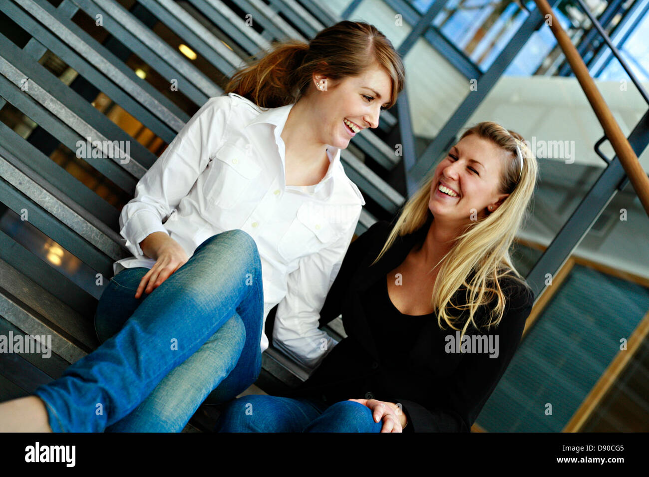Two smiling women sitting on the stairs Stock Photo - Alamy