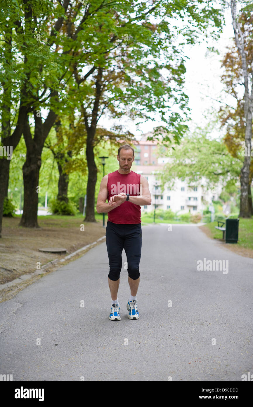 Male jogger checking time in park Stock Photo - Alamy