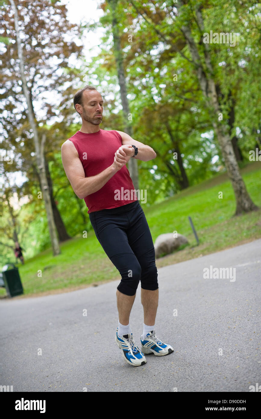 Male jogger checking time in park Stock Photo - Alamy