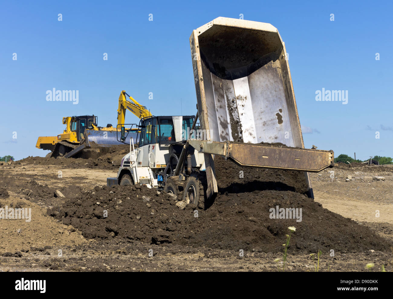Dump truck unloading earth on construction site Stock Photo - Alamy