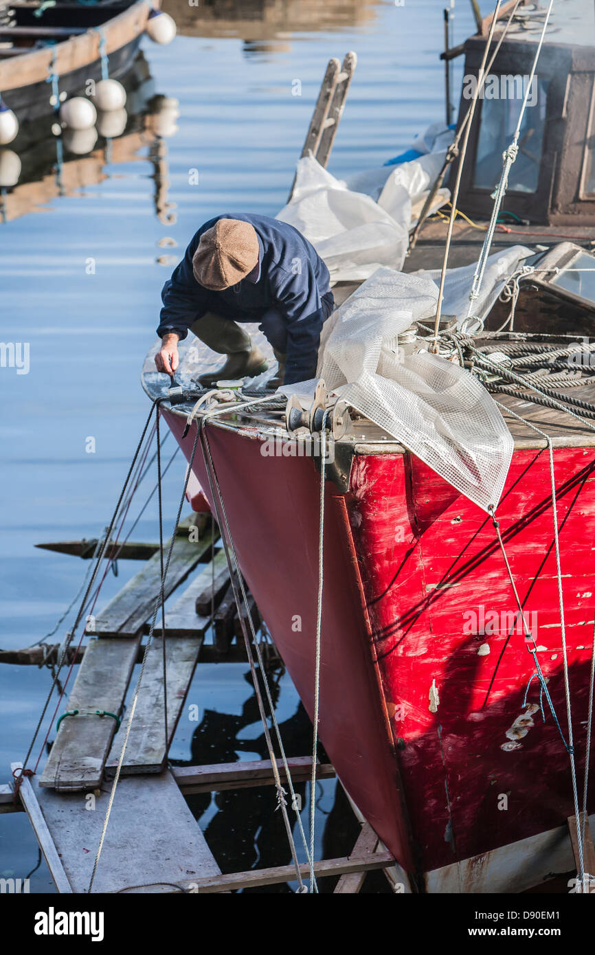 Man working on boat at Corrie on the Isle of Arran in Scotland Stock ...