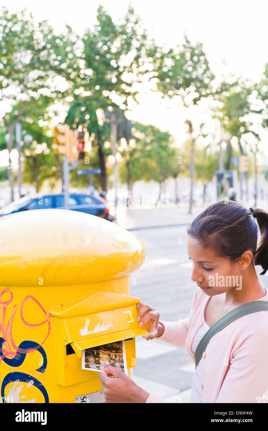 Woman posting postcard to postbox Stock Photo - Alamy