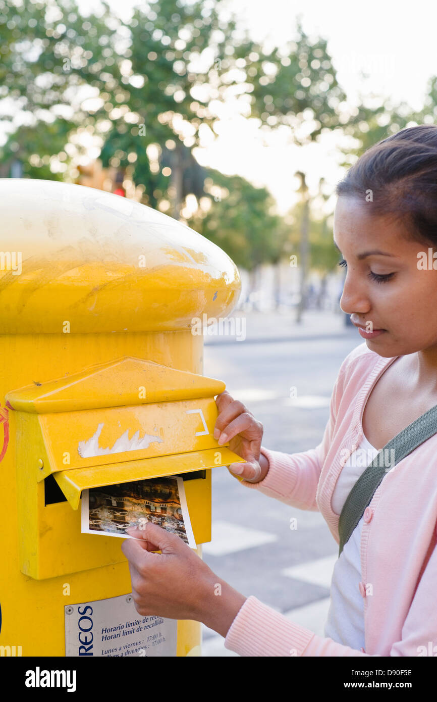 Woman putting postcard into letterbox Stock Photo - Alamy