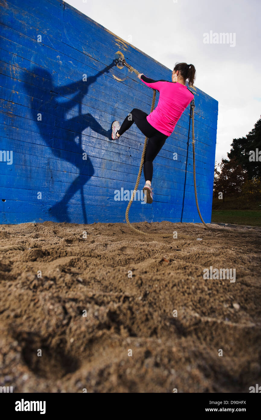 Woman climbing wall using rope in obstacle course Stock Photo - Alamy