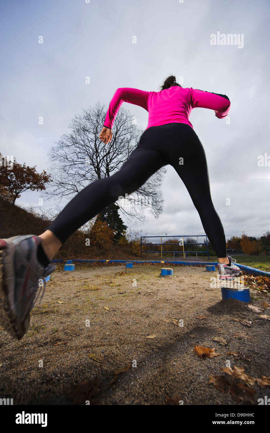 Woman jumping from one log to other Stock Photo - Alamy