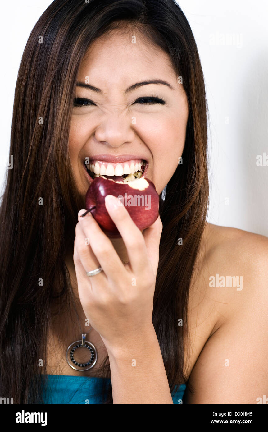 Studio portrait of young woman eating apple Stock Photo - Alamy