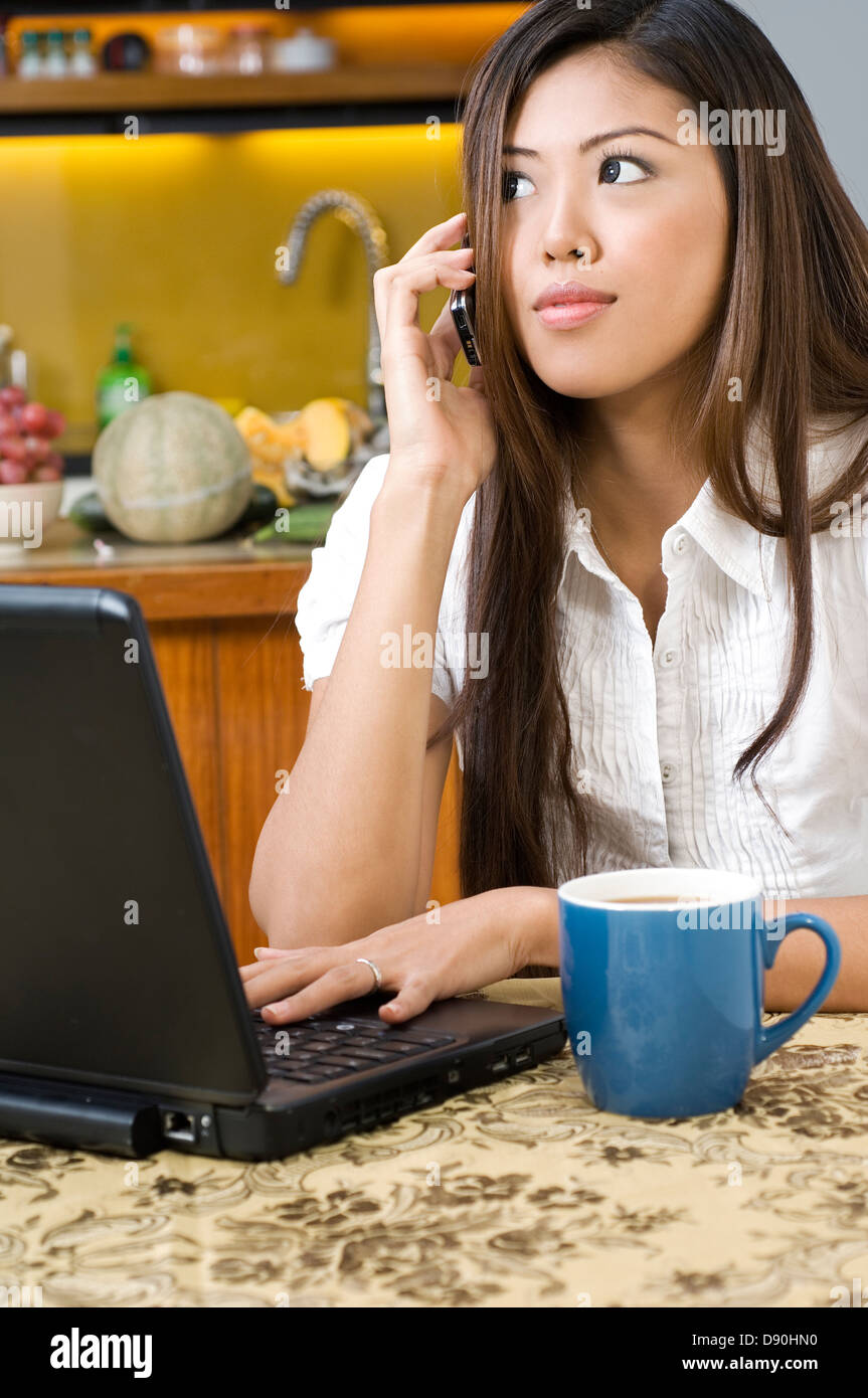 Philippines, young woman working on laptop in kitchen Stock Photo - Alamy