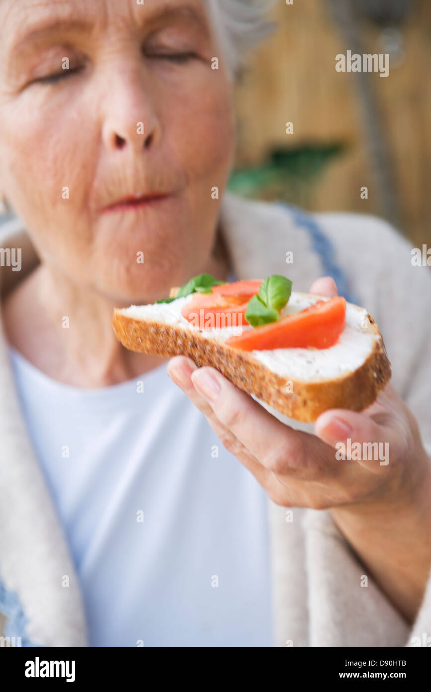 Woman eating a sandwich with cheese, tomato and basil, Sweden Stock ...