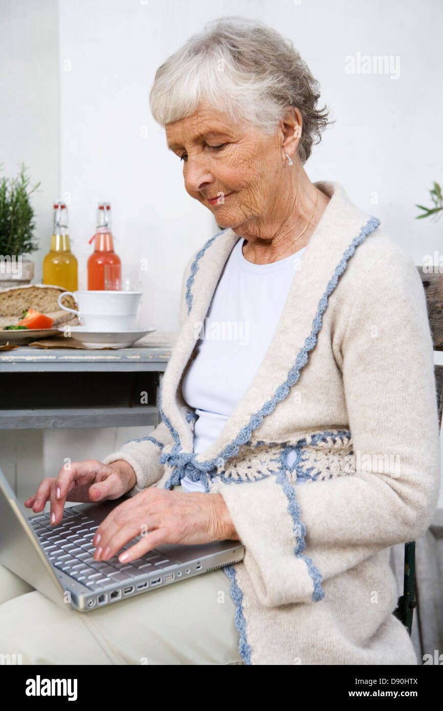 An older woman writing on her computer, Sweden Stock Photo - Alamy