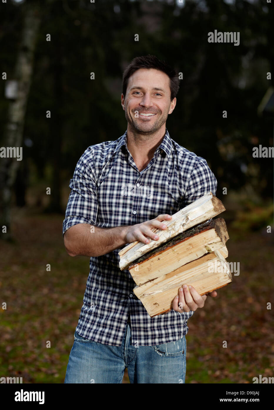 Man holding chopped firewood, smiling, portrait Stock Photo - Alamy