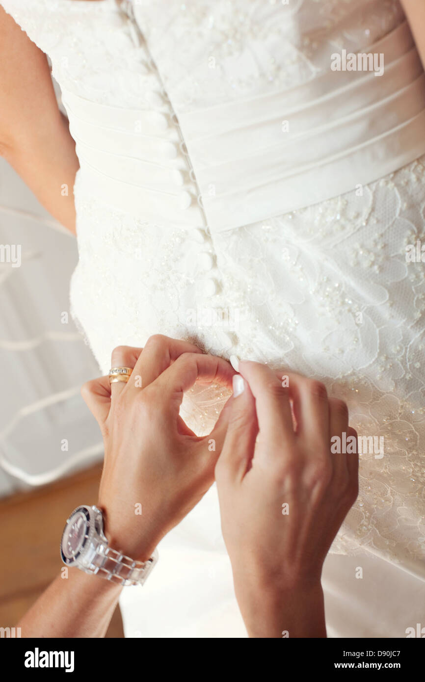 Woman buttoning wedding dress on friend Stock Photo - Alamy