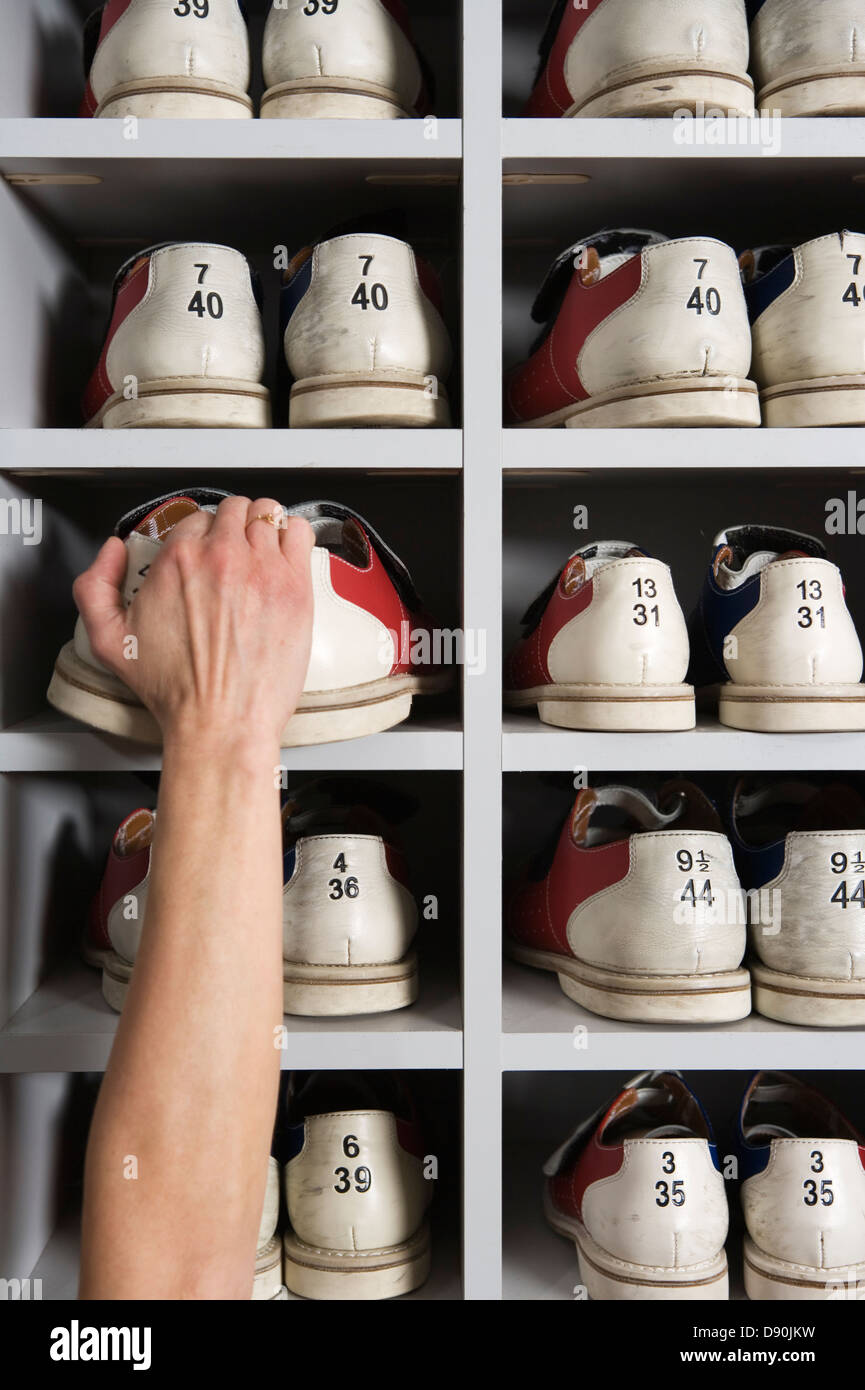 Hand picking shoes on shelves in a bowling alley Stock Photo - Alamy