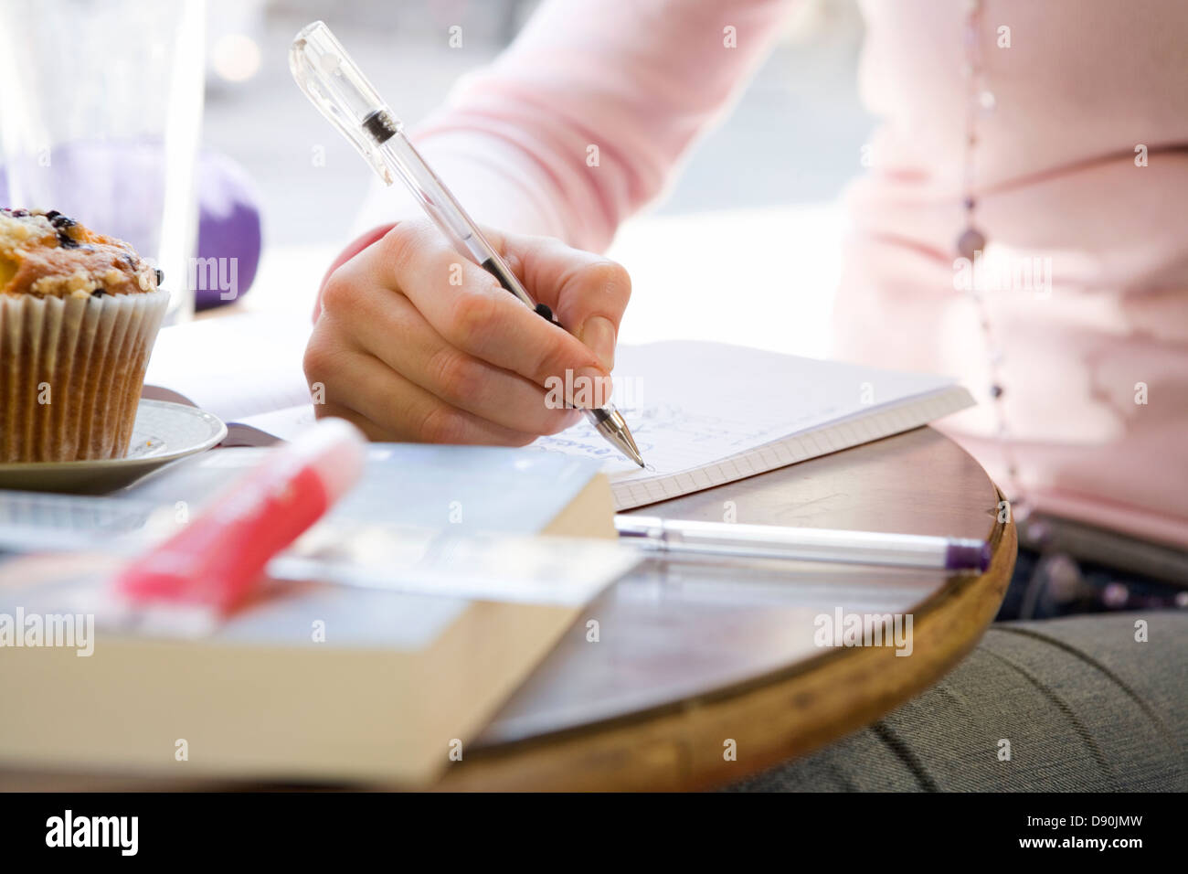 A woman writing in her note book in a cafe Stock Photo - Alamy