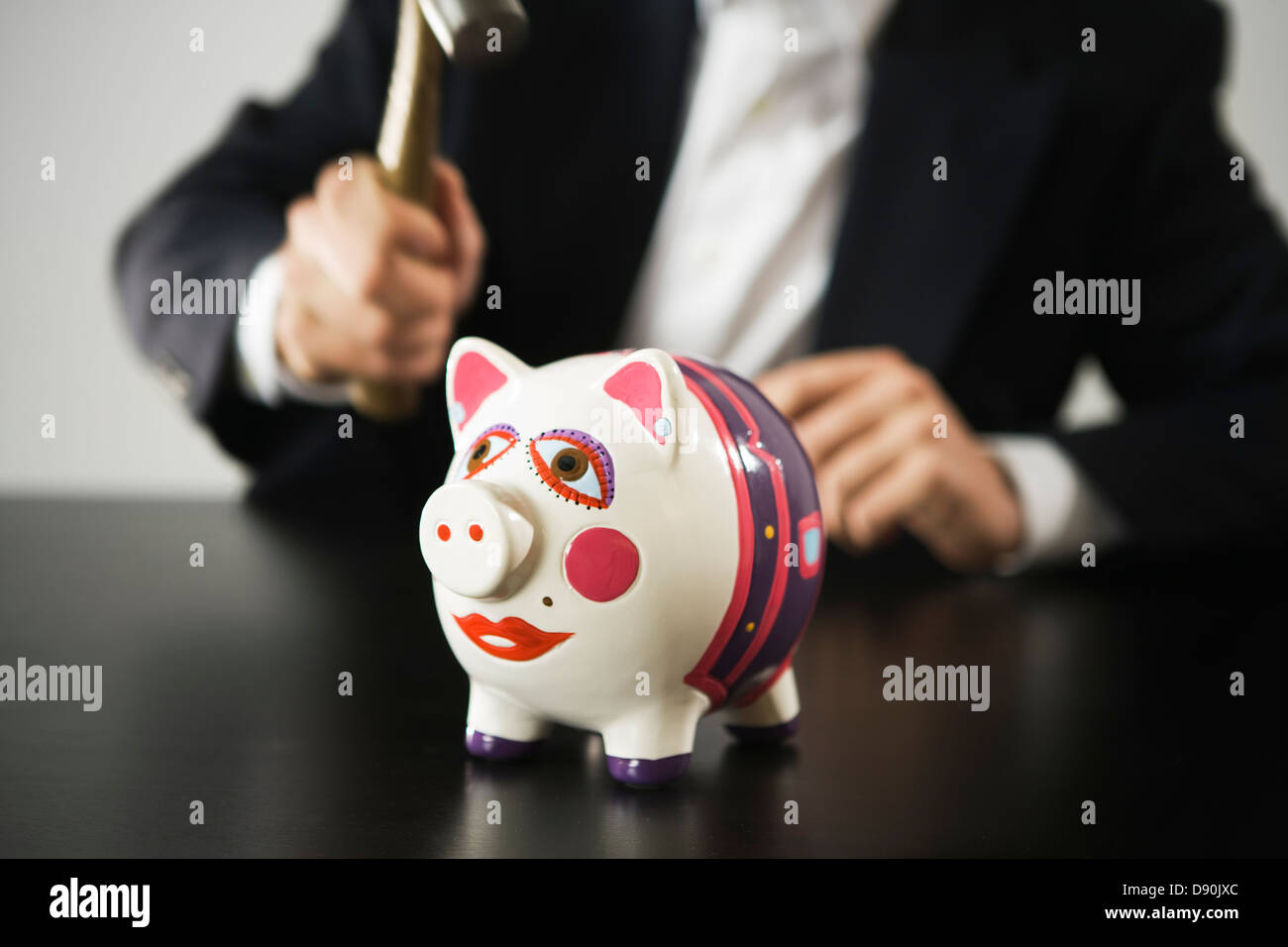 A man breaking a piggy bank with a hammer Stock Photo - Alamy
