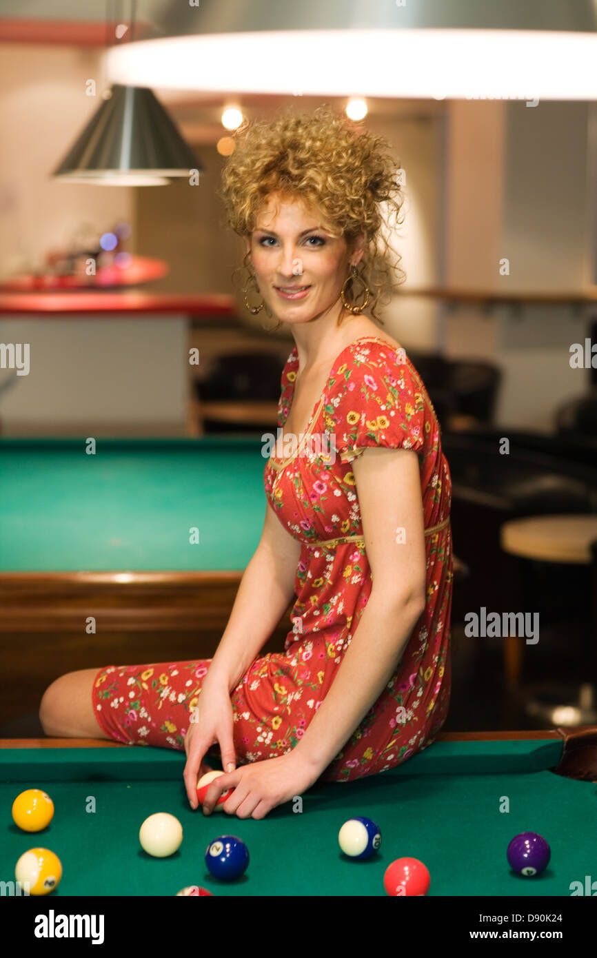 Woman sitting on a billiard table Stock Photo - Alamy