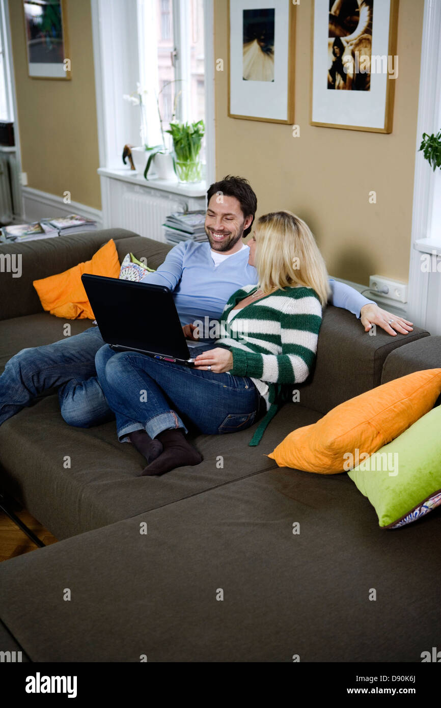 A couple with a computer in a sofa Stock Photo - Alamy