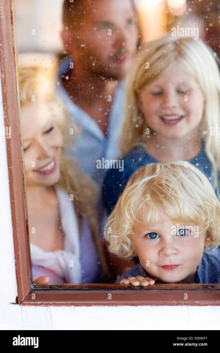 Family standing beside window, smiling Stock Photo - Alamy