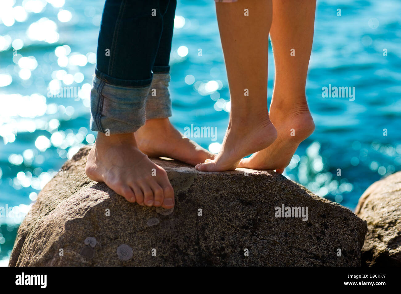 Couples feet on rock beside sea Stock Photo - Alamy