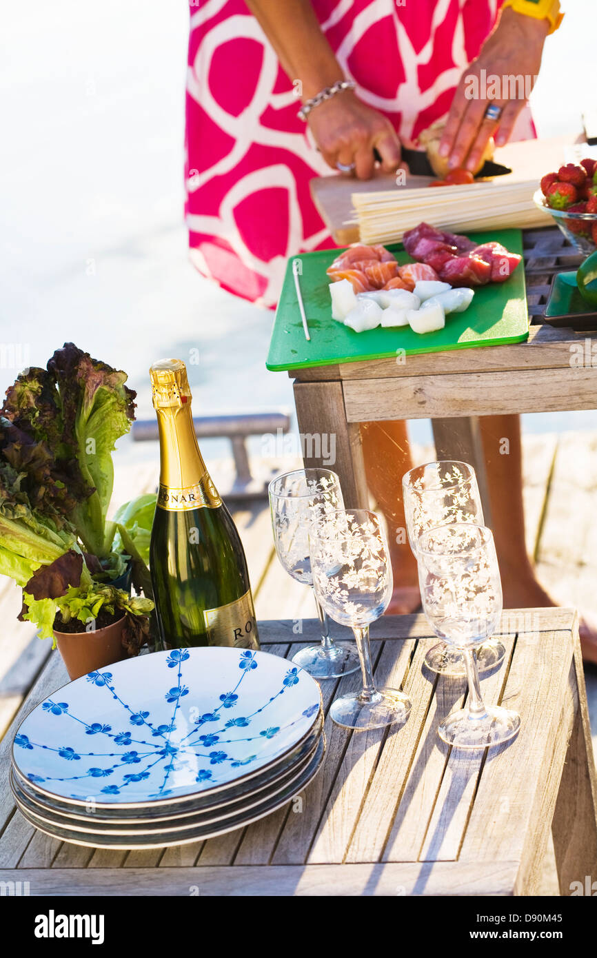 Woman standing by table on jetty, preparing food Stock Photo - Alamy