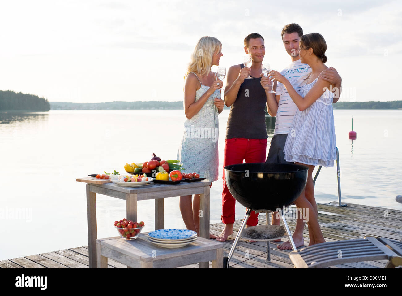 Four people standing on jetty and toasting with glasses Stock Photo - Alamy