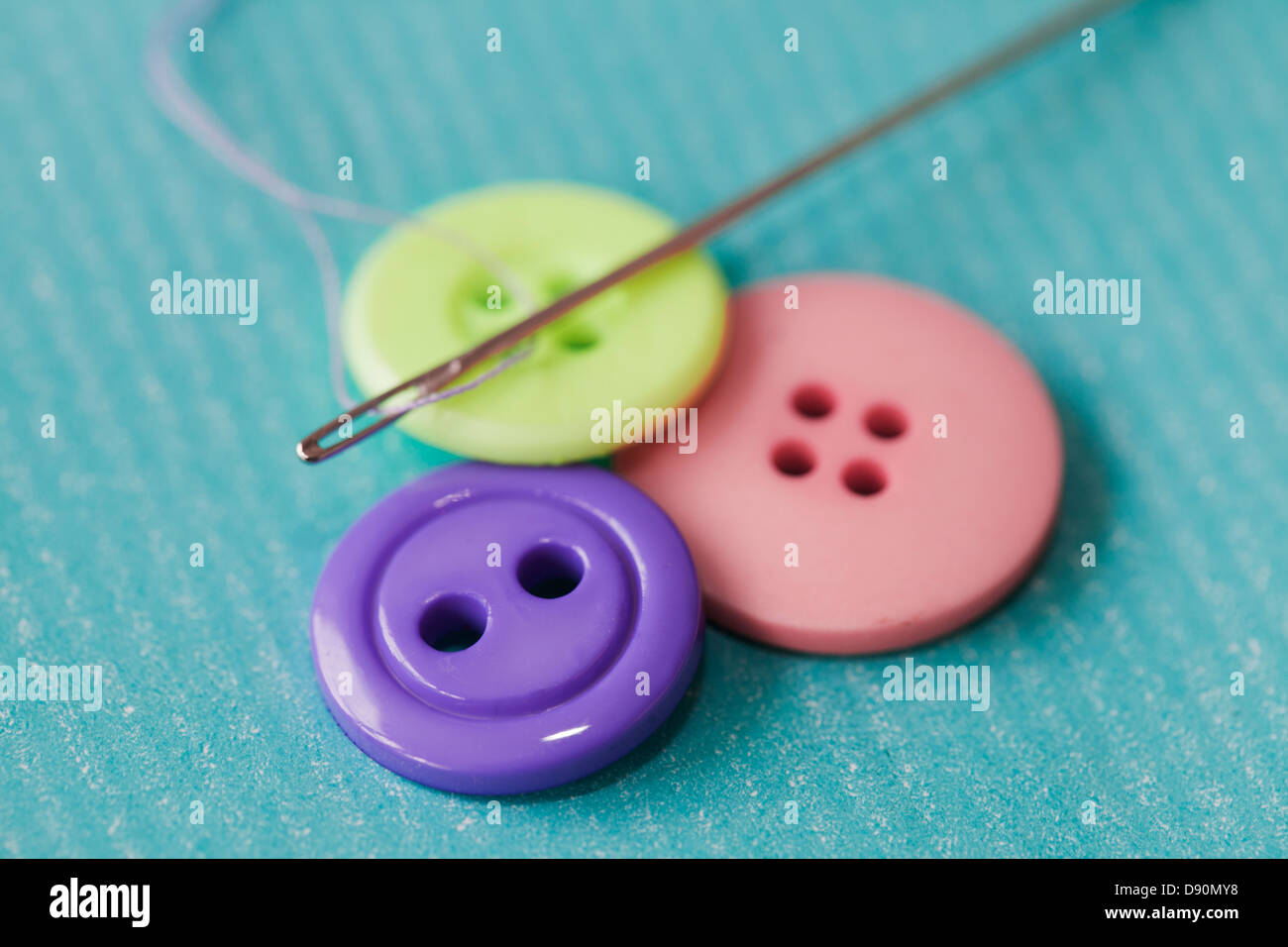 Needles on top of multi coloured buttons Stock Photo - Alamy