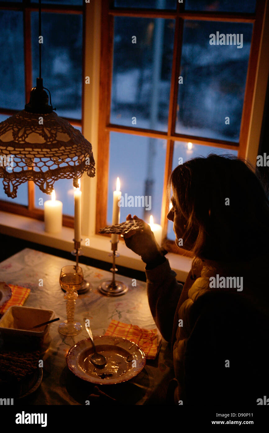 Woman eating dinner in restaurant with candles burning in background ...