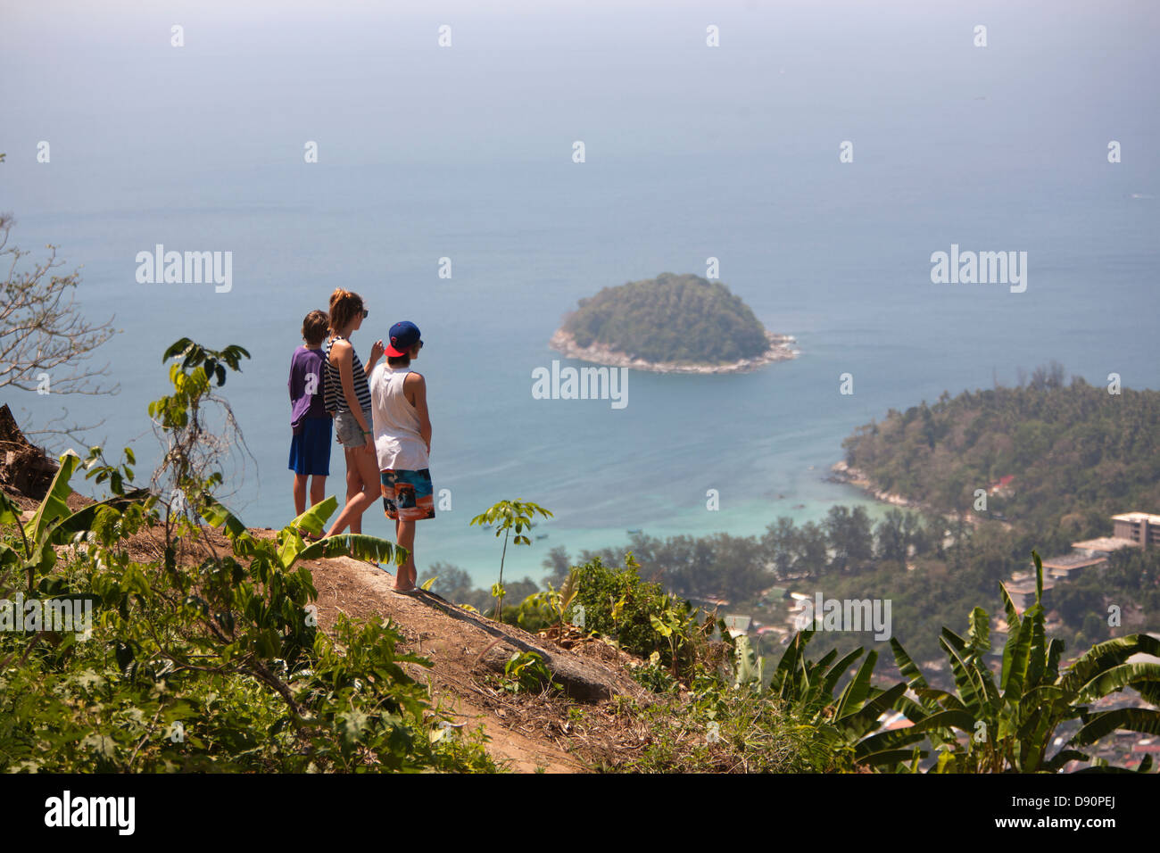 Three teenagers viewing island in sea from cliff Stock Photo - Alamy