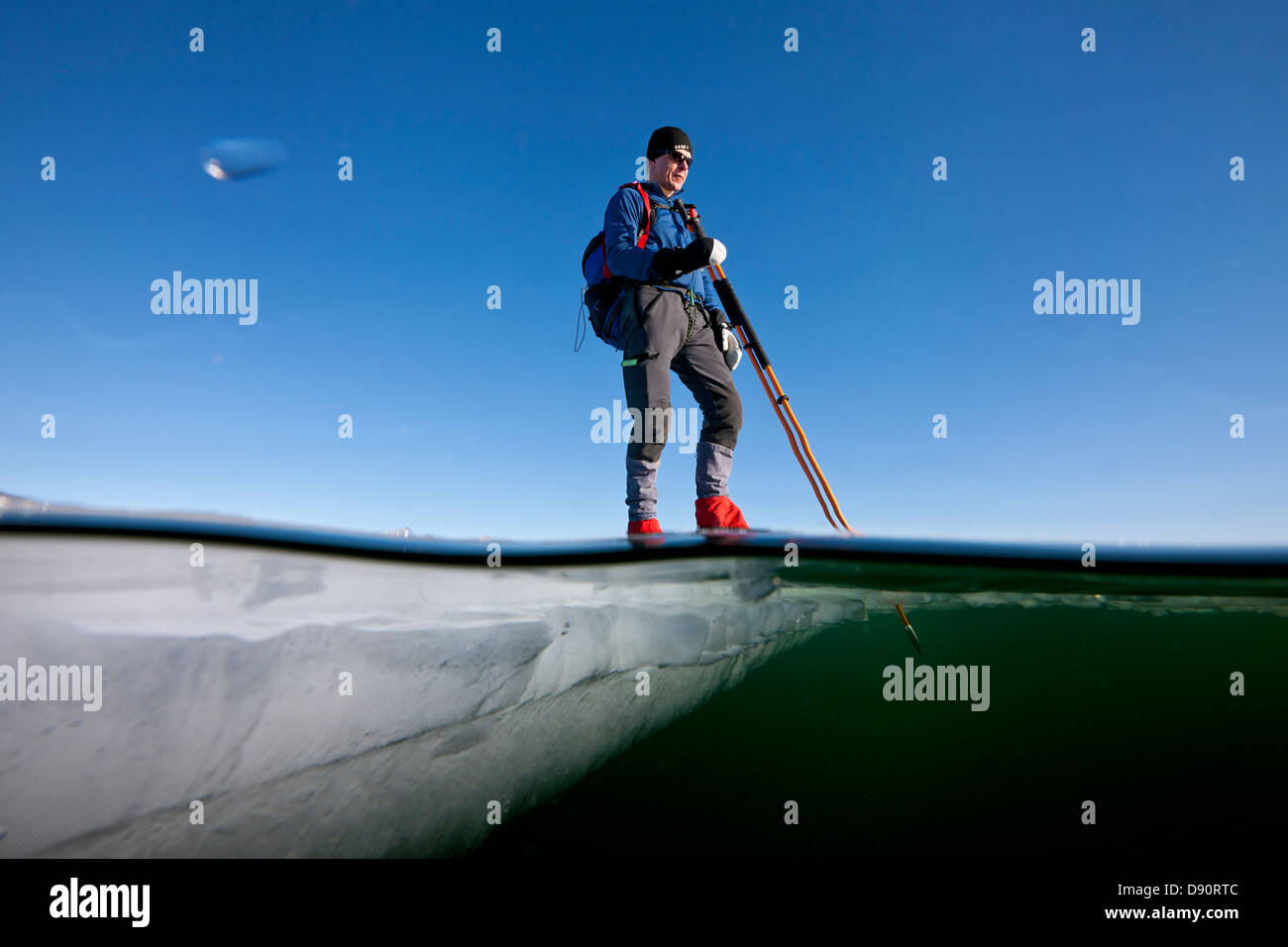 Man standing on ice with pole Stock Photo - Alamy