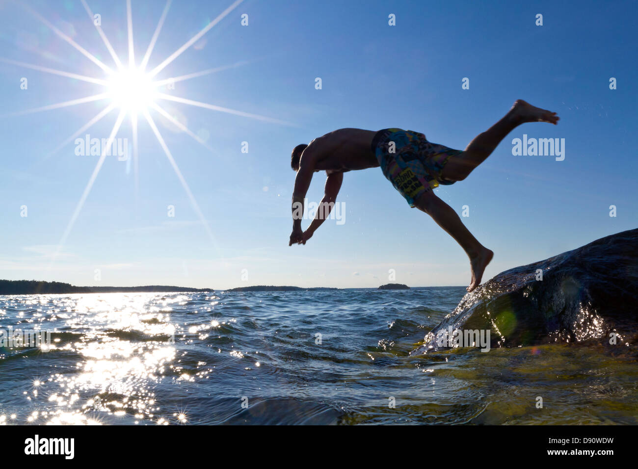 Young man jumping into water Stock Photo - Alamy